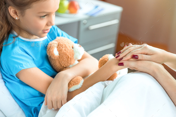 Doctor and little patient with teddy bear holding hands in hospital ...