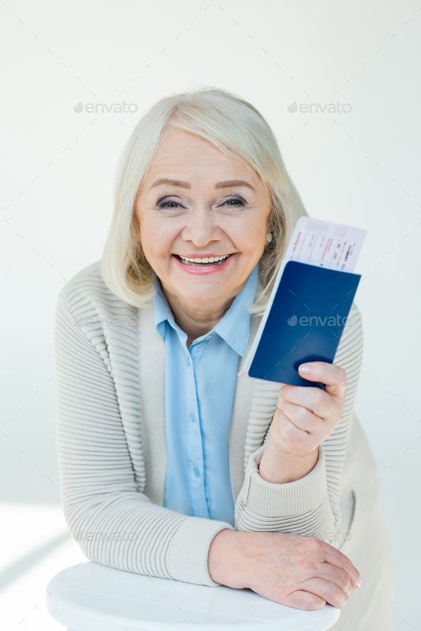 Portrait Of Happy Senior Woman Showing Passports And Tickets Traveling