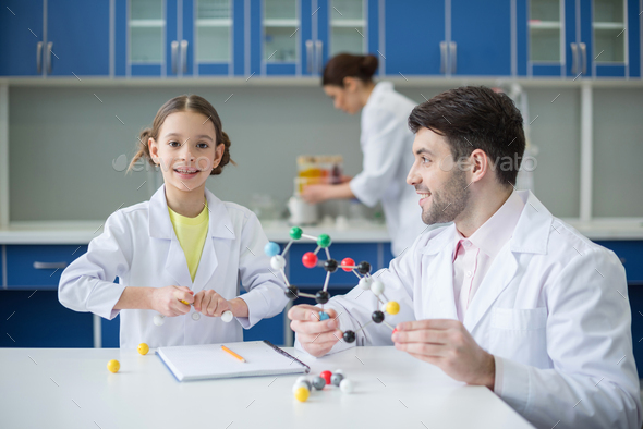 Smiling teacher and student scientists working with molecular model in ...