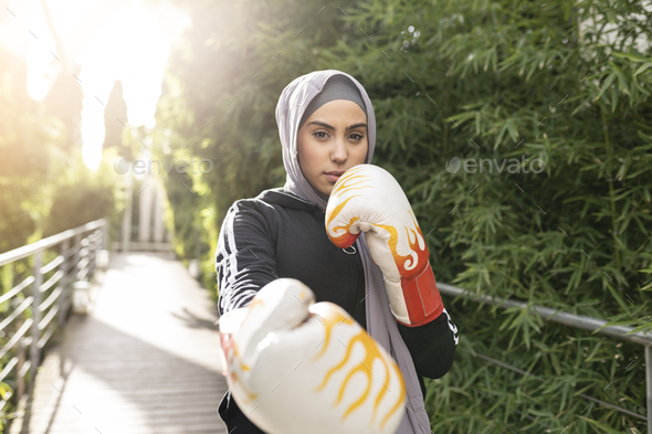 Arab female athlete of islamic faith practicing boxing outdoors ...