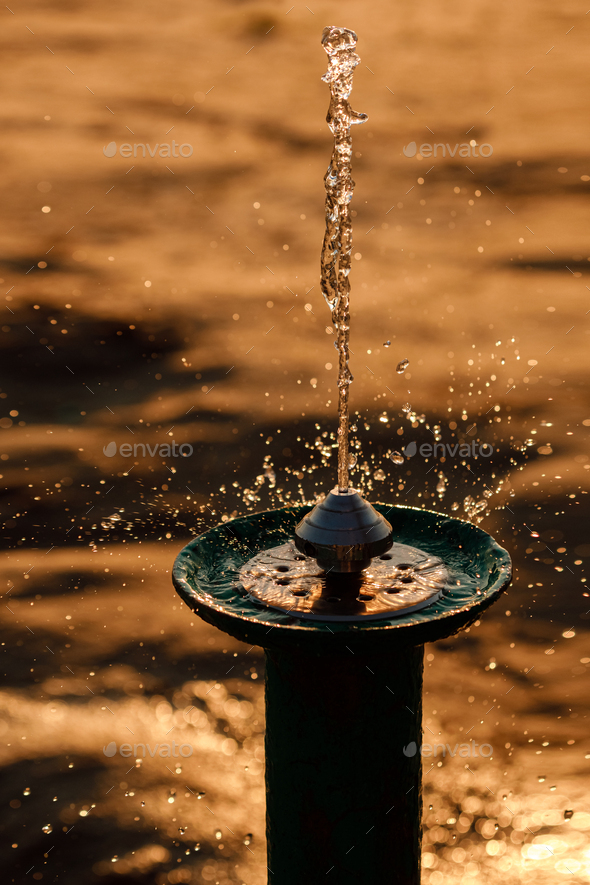 Drinking fountain with flowing water on the beach near lake on sunset ...
