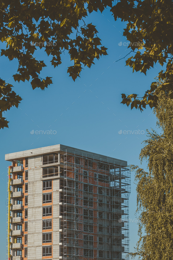 Large skyscraper building under construction and green treetop Stock ...
