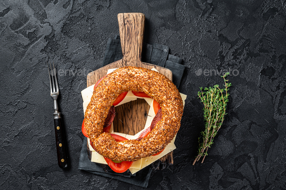 Simit bagel sandwich with lettuce, tomato, yellow cheese and ham. Black ...