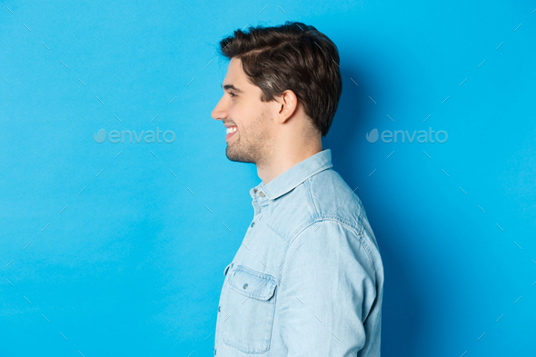 Profile of handsome young man looking left, smiling happy, standing ...