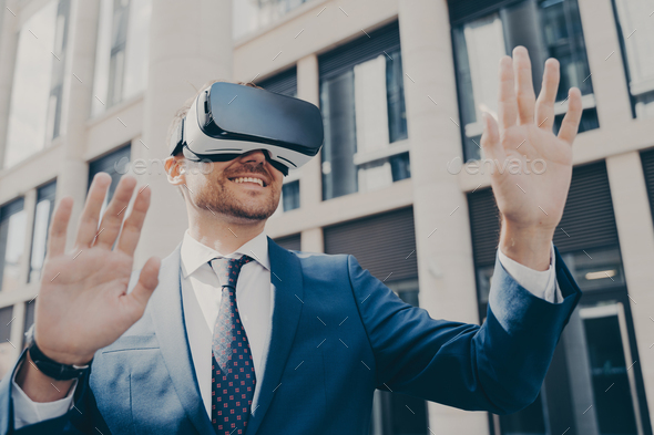 Professional impressed worker standing outside alone and using VR ...