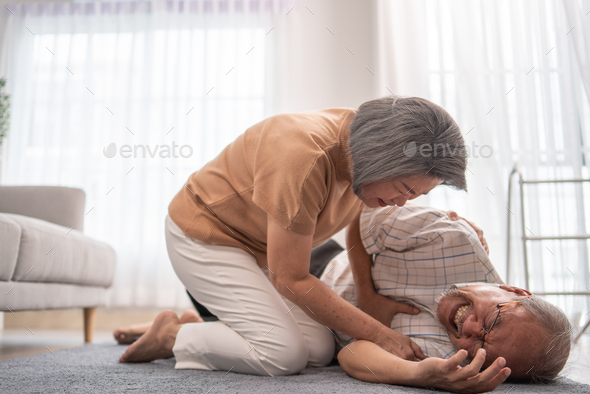 Asian senior wife helping husband fainting and falling on the ground ...