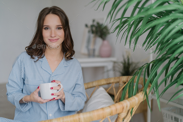 Image of relaxed woman with pleasant appearance, dressed in night ...