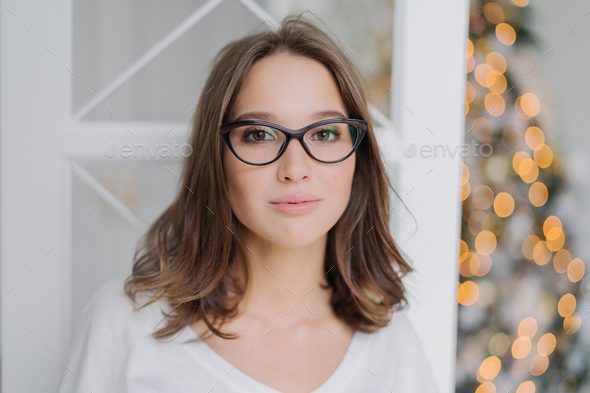 Headshot of lovely young female model in transparent glasses, has dark ...