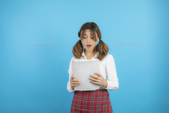 Shocked young college girl holding her notes and looking at them. Stock ...