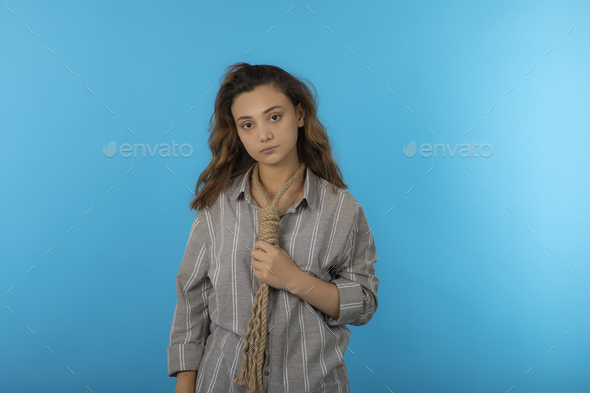 A depressed young girl put a rope around her neck and looking at camera ...