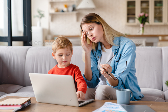 Busy exhausted tired stressed depressed young mother working remotely ...