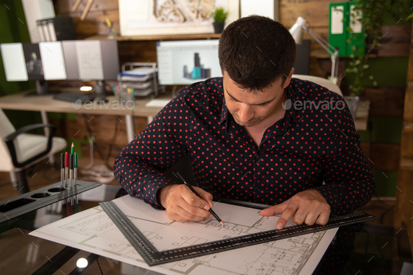Male architect drawing a new project on the sheet Stock Photo by DC_Studio