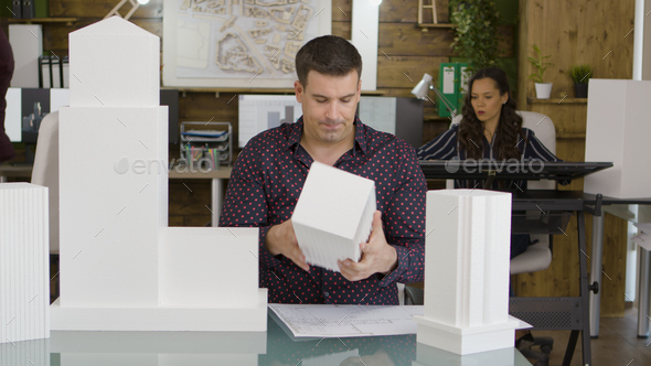 Male architect looking at a 3D printed model of a real building Stock ...