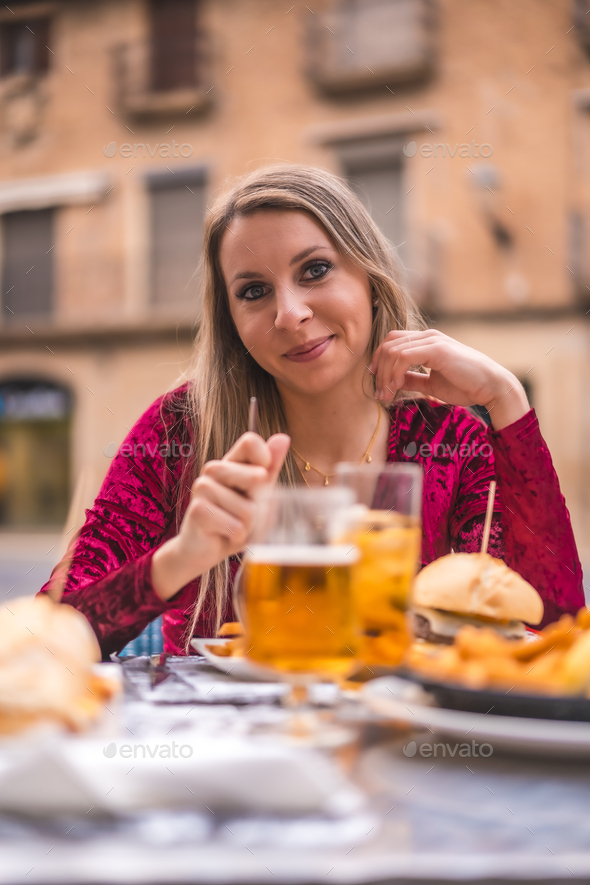 Blonde woman eating lunch in a red dress next to a medieval castle ...