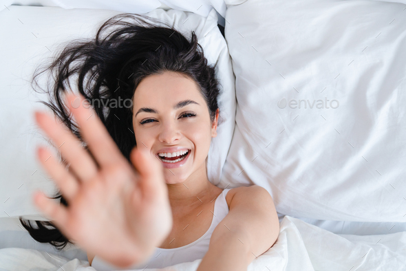Young white woman doesn`t want to get up from her cosy bed early in the ...