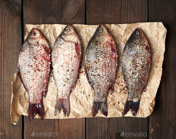 Whole fresh crucian fish with scales on a crumpled brown piece of paper ...