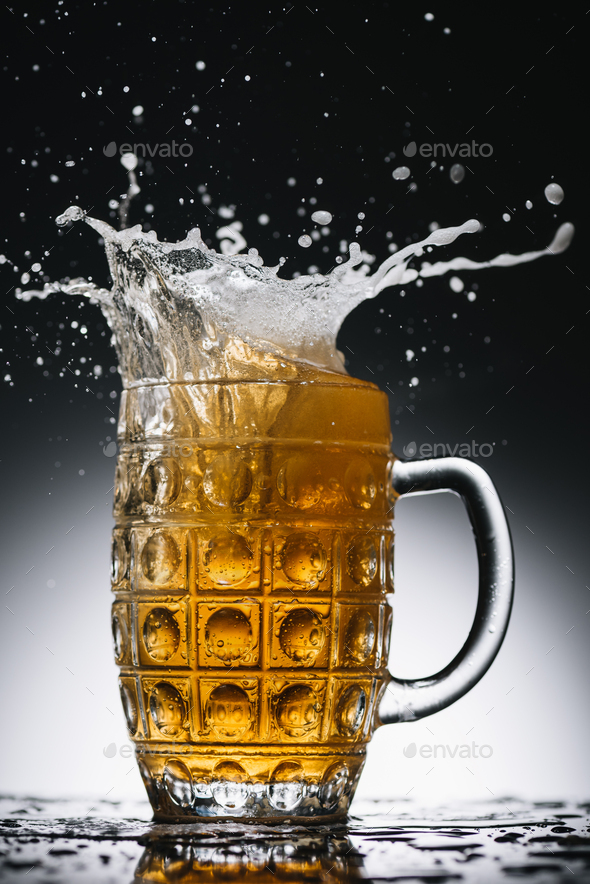 splashes of cold light beer in mug Stock Photo by LightFieldStudios