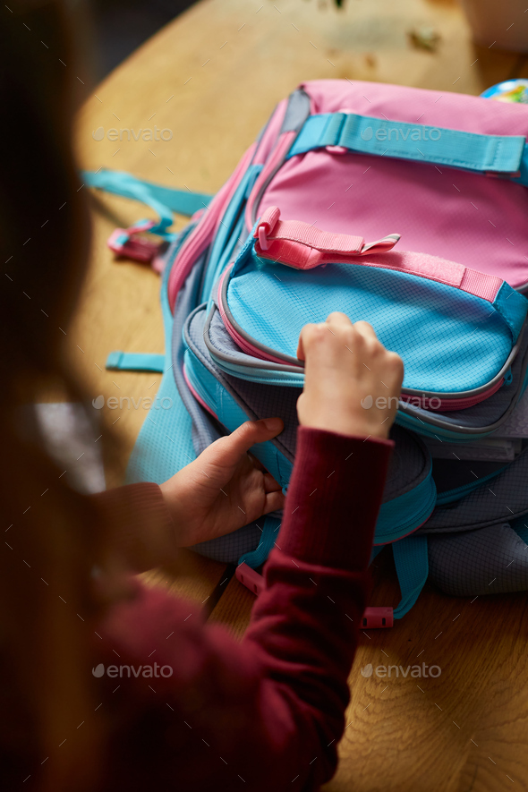 Schoolgirl put books and notes into backpack at home, pupil prepare ...