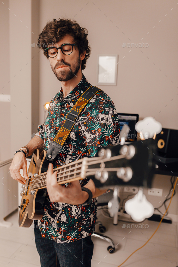 Millennial musician plays bass guitar Stock Photo by carlesmiro | PhotoDune