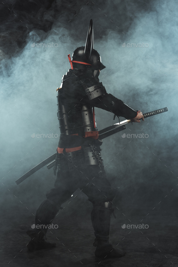 side view of samurai taking out his katana on dark background with ...