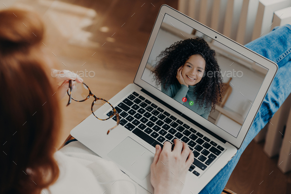 View from shoulder of woman greets best friend via laptop computer ...