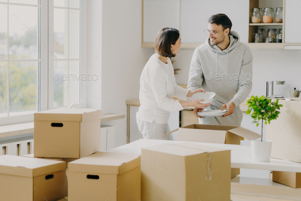 Photo of busy family couple unpack personal stuff from carton boxes ...