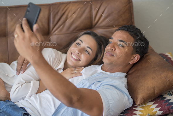 Young couple in love enjoy and use modern mobile phone together laying ...