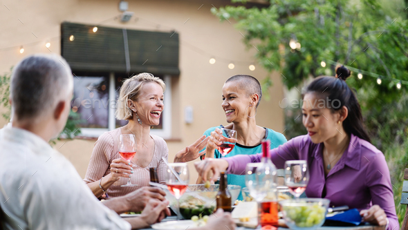 Women friends having fun at summer dinner, talking and eating healthy ...