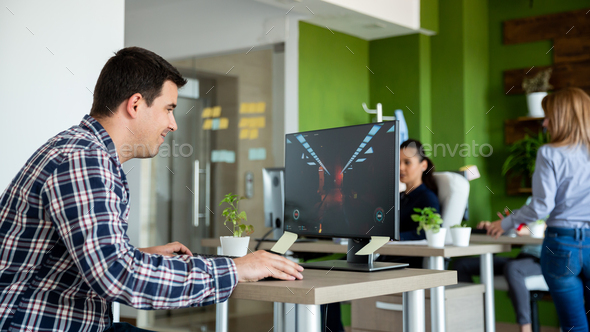 Man playing video games during working hours Stock Photo by DC_Studio