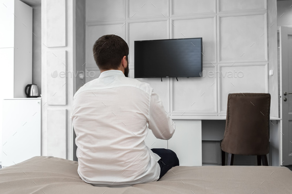 Young man using TV remote control Stock Photo by FabrikaPhoto | PhotoDune