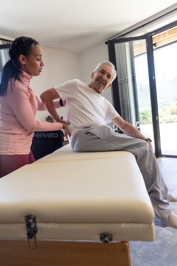 Biracial female physiotherapist giving back massage therapy to ...
