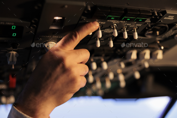 Aviation pilot using control panel in cockpit to fly airborne aircraft ...