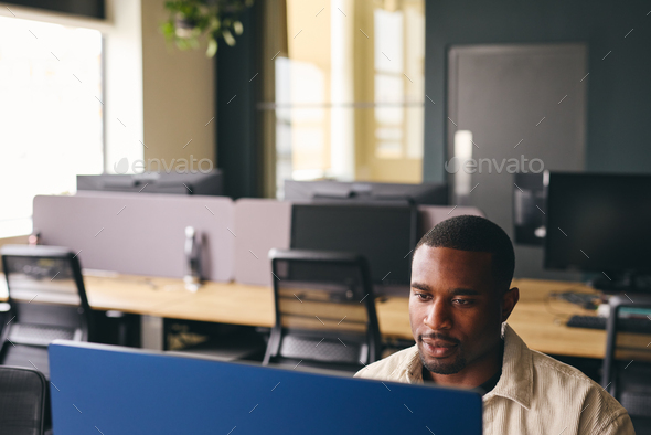 Young black man working on computer in modern office at desk Stock ...