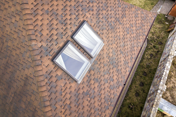 Close-up of new small attic plastic windows installed in brown shingled ...