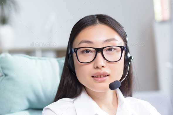 Close up photo. Portrait of a young beautiful Asian woman in headphones with a microphone. Stock ...