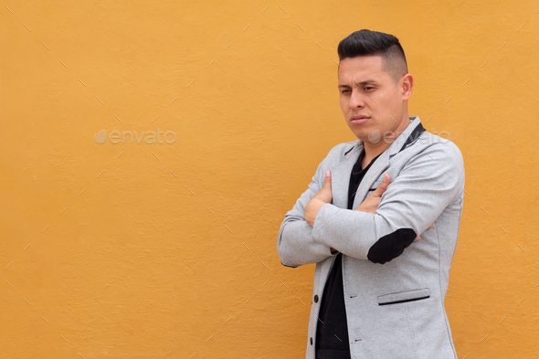 Indignant man with low and somewhat angry look on orange-yellow ...