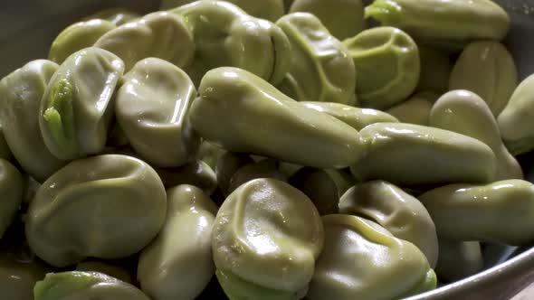 Close up of Fava beans spinning. The beans have been boiled so the skin ...