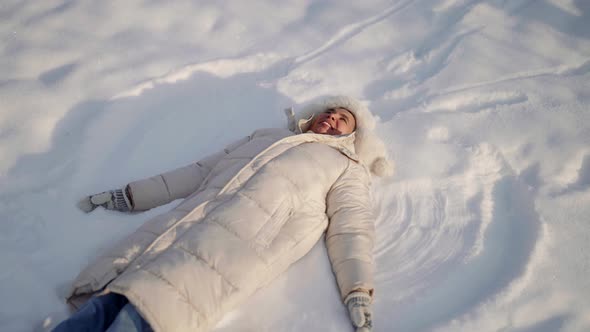 Making Angel on Snow Joyful Man is Lying on Snowdrift and Moving Hands ...