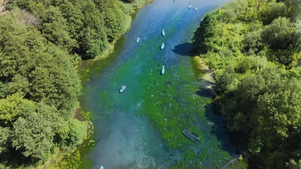 Group of paddlers are paddling along azure river. Vacationers enjoy the ...