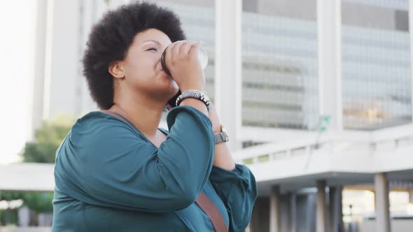 Happy plus size biracial woman talking on smartphone and drinking ...