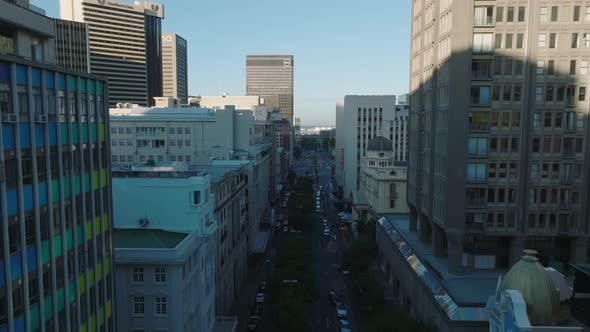 Backwards Fly Above Wide Boulevard Surrounded By Tall Buildings in City ...