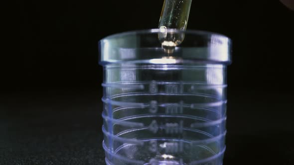 Drops of Experimental Vaccine Fall Down Into Plastic Flask, Stock Footage