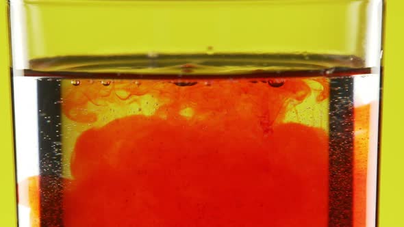 Close Up Footage of Red Ink Dripping Into Clear Water on Yellow ...
