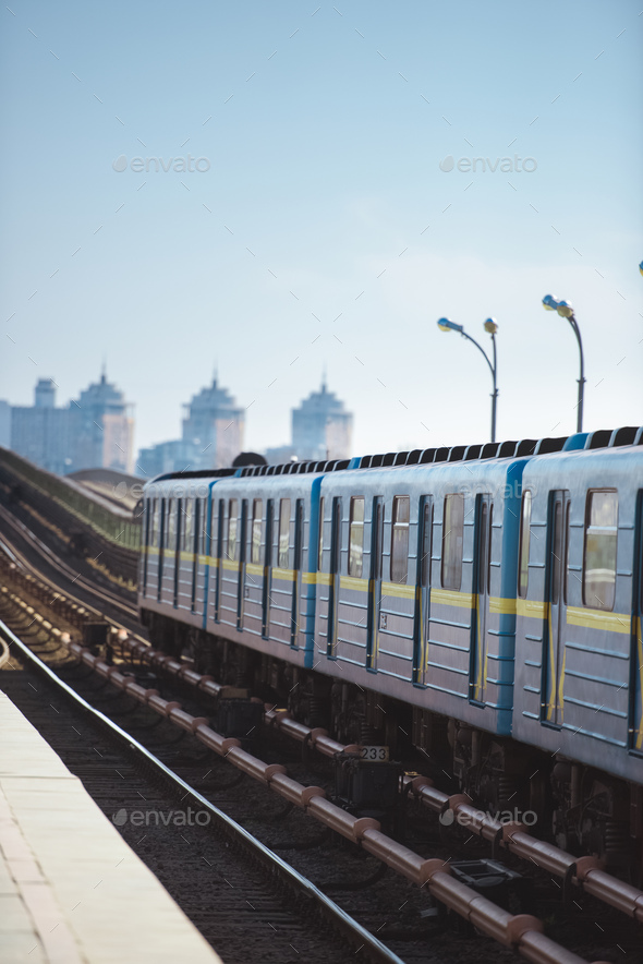 front view of train at outdoor subway station with buildings on ...