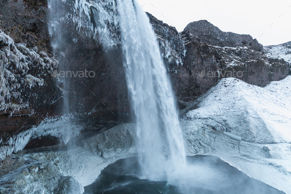 magnificent landscape with Seljalandsfoss waterfall and rocks in snow ...
