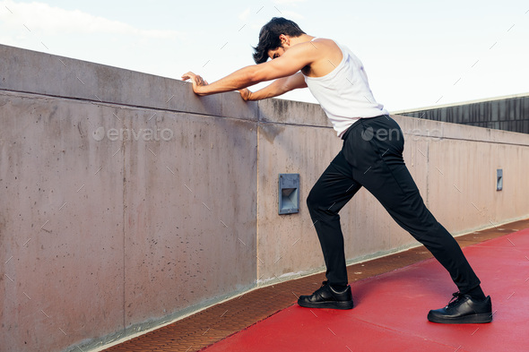 sportsman stretching legs on a concrete wall Stock Photo by Raul_Mellado