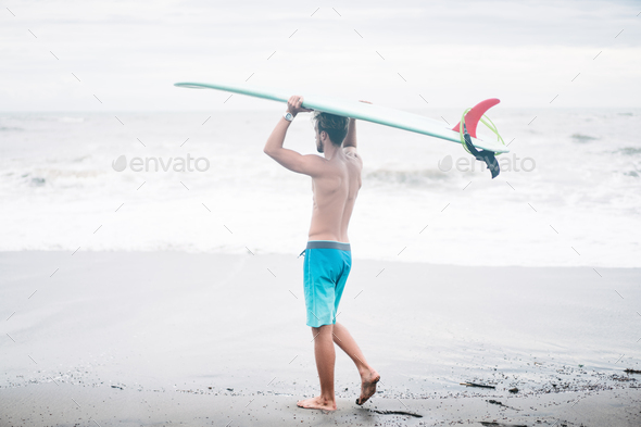 side view of surfer carrying surfboard on head in Bali, Indonesia Stock ...