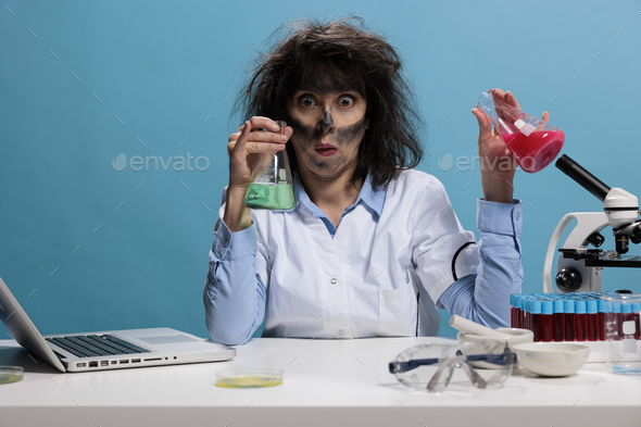 Mad silly looking crazy lab worker sitting at desk while having glass ...