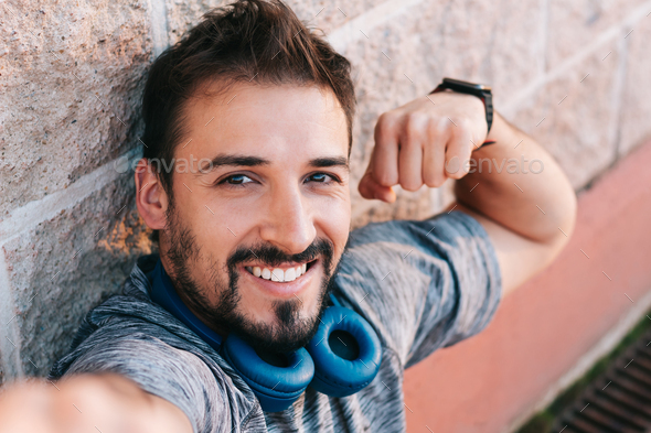 young adult man looking at the camera while showing his bicep muscle by ...