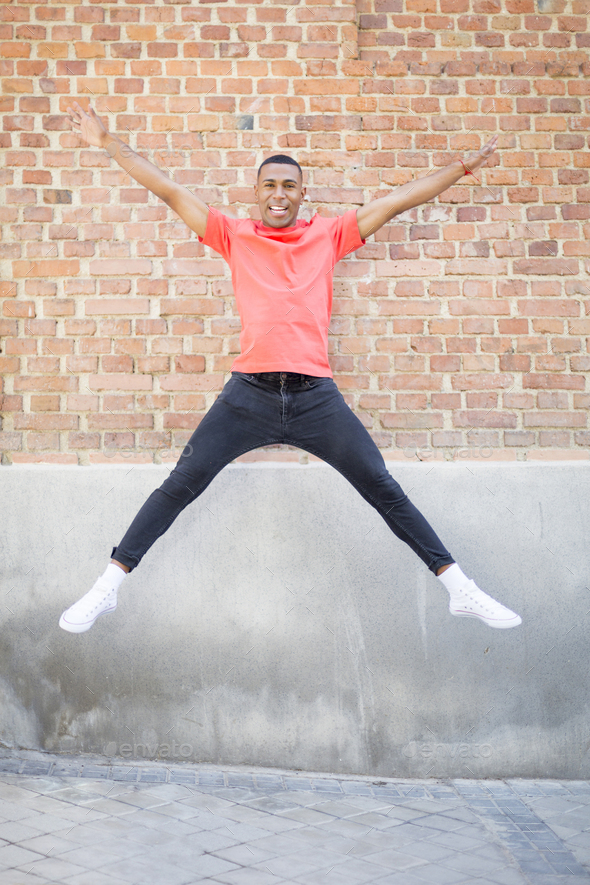 young african american man jumping with open legs looking at camera ...